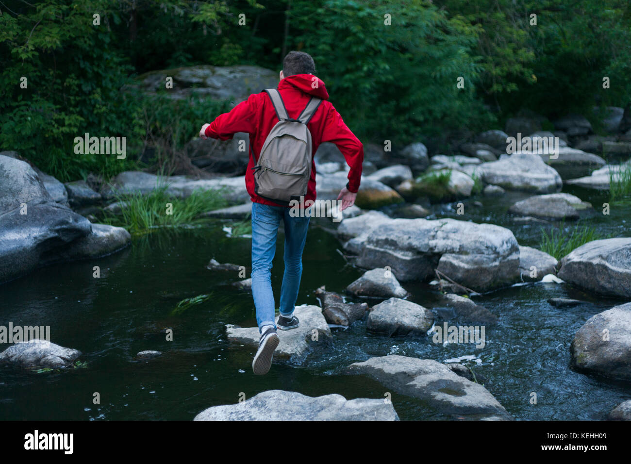 Caucasian man walking on rocks crossing river Stock Photo - Alamy