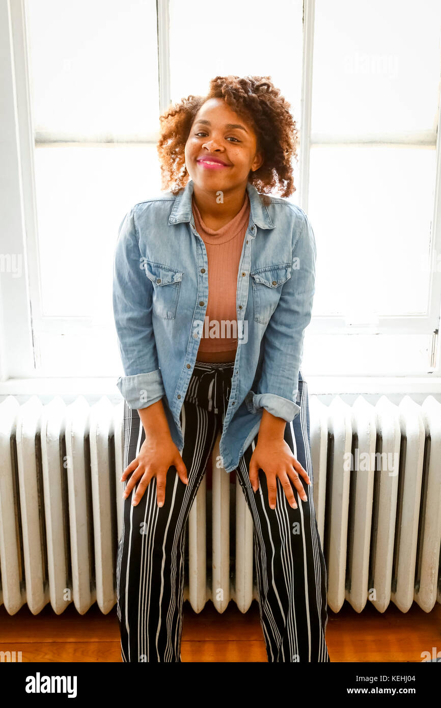 Smiling mixed race woman sitting on radiator Stock Photo - Alamy