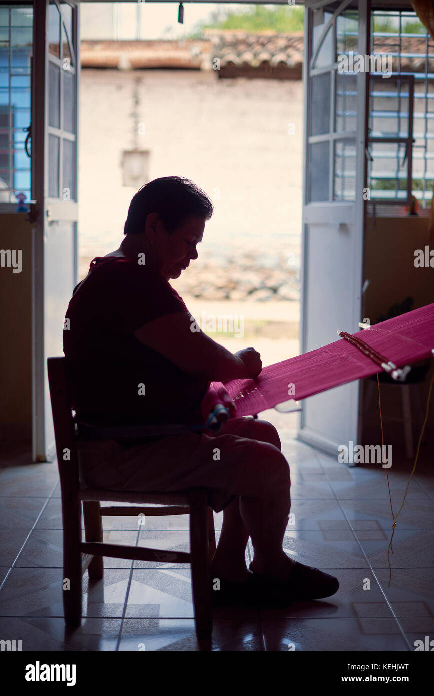 Hispanic woman weaving fabric on loom near doorway Stock Photo - Alamy