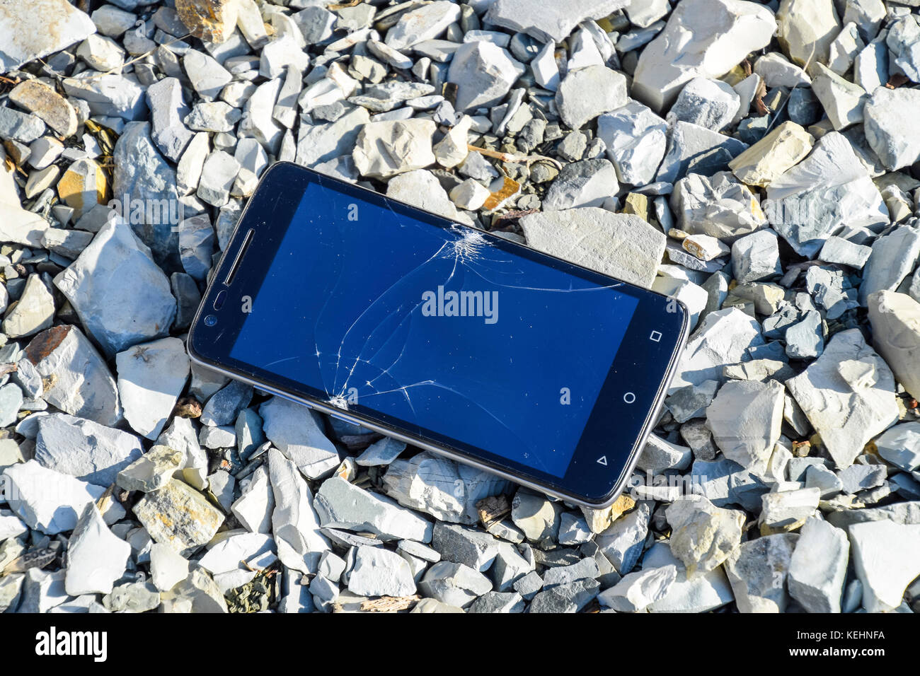 Frustrated phone on the rocks. Glass shattered on rocks on a smartphone ...