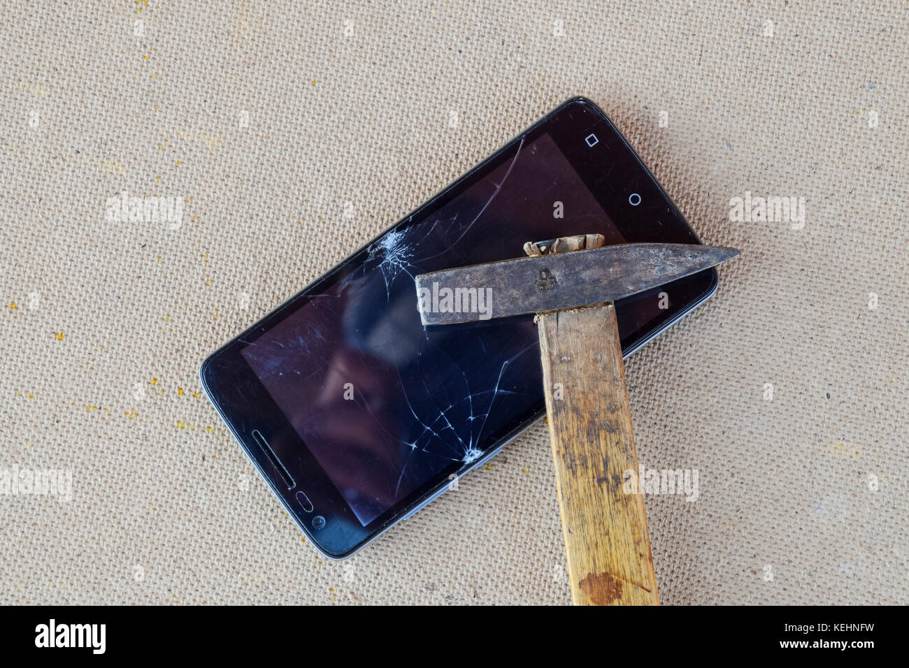 Hammer and smartphone. The screen of the smartphone, a broken hammer ...