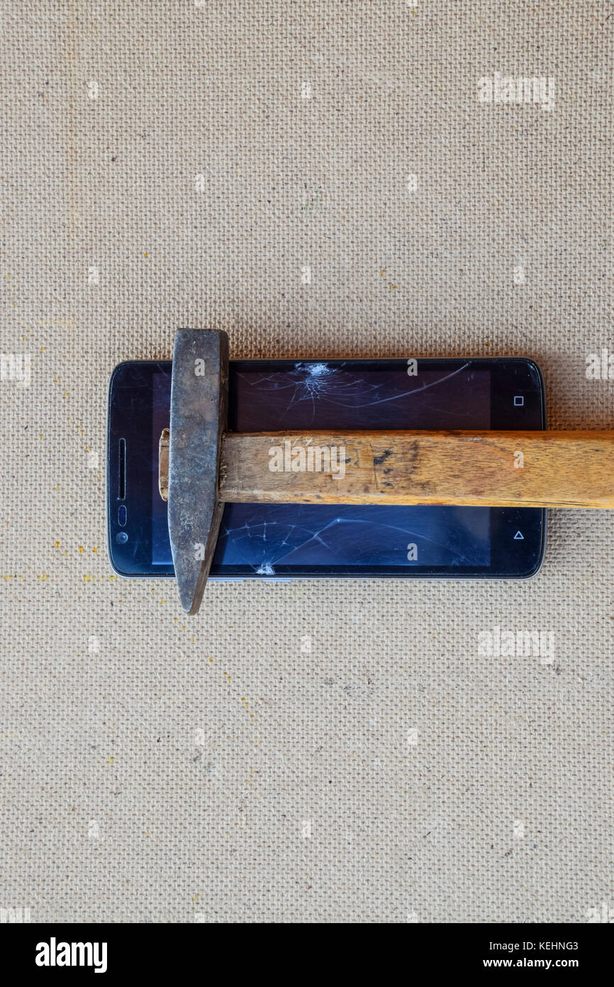 Hammer and smartphone. The screen of the smartphone, a broken hammer ...