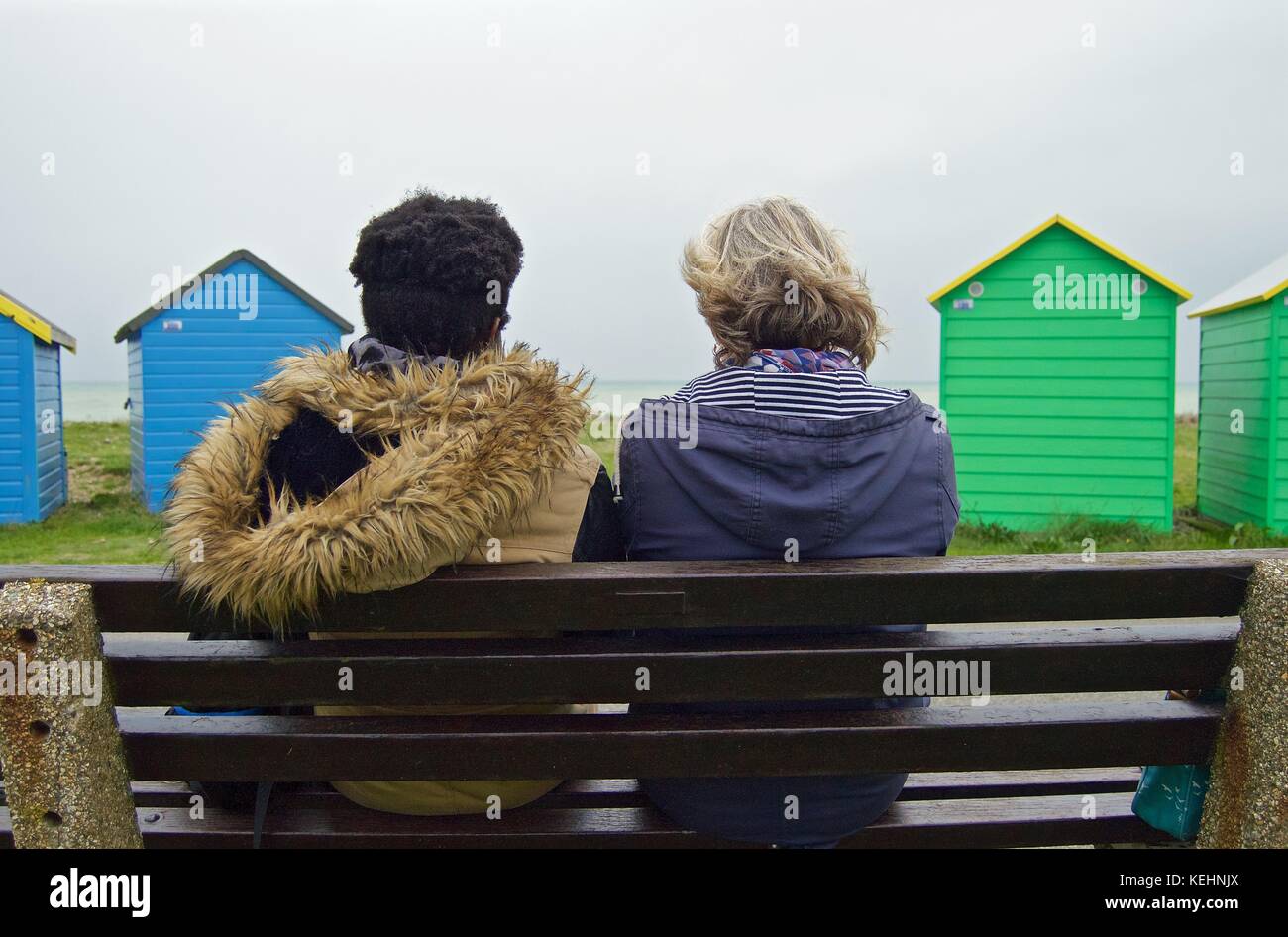 Woman sitting on bench in front of beach huts hi-res stock photography ...