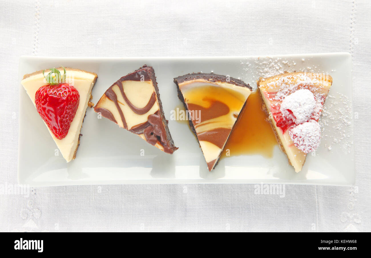 Four cheesecake portions topped with fresh berries, chocolate and ...