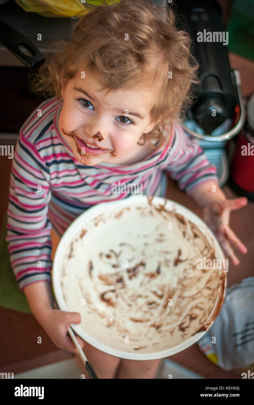 Young girl cleaning a chocolate bowl after making cake Stock Photo - Alamy
