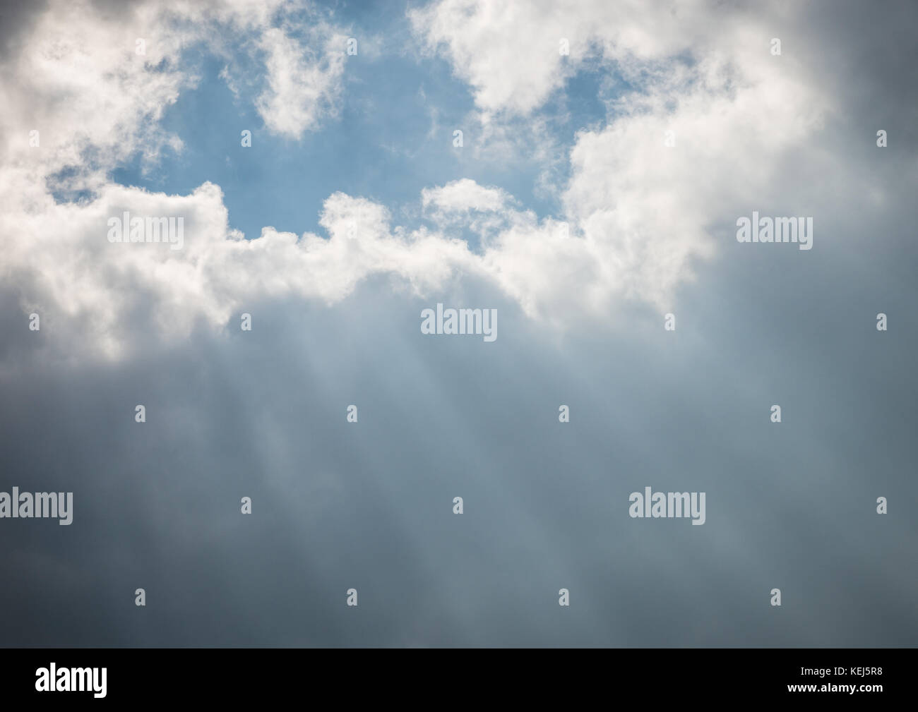 Rays of light shine through the dark surrounding clouds Stock Photo - Alamy
