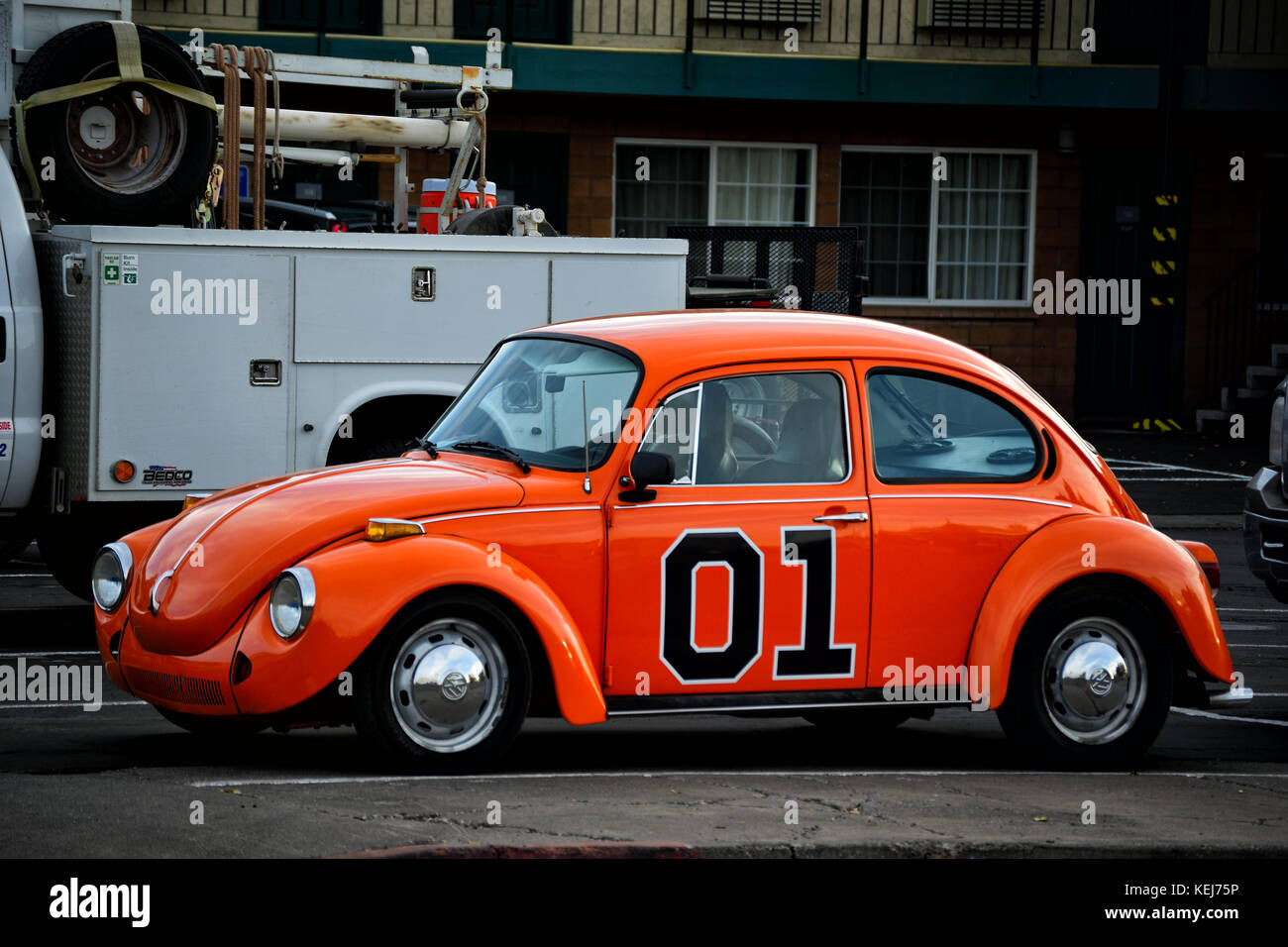 An orange VW Beetle with racing numbers on its side in a motel parking ...