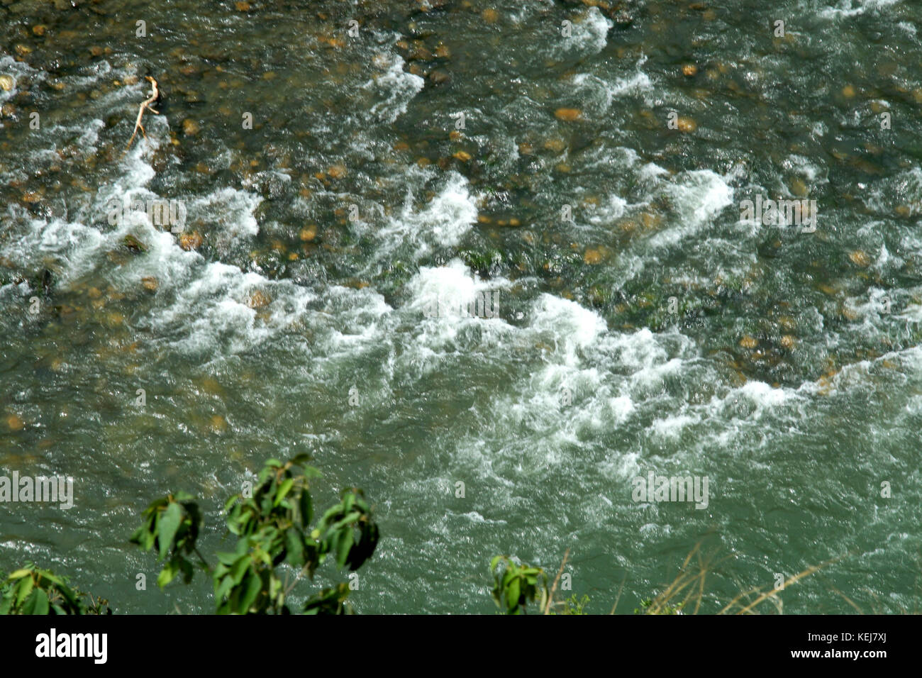 Water in river flowing forcefully while passing through Stock Photo - Alamy