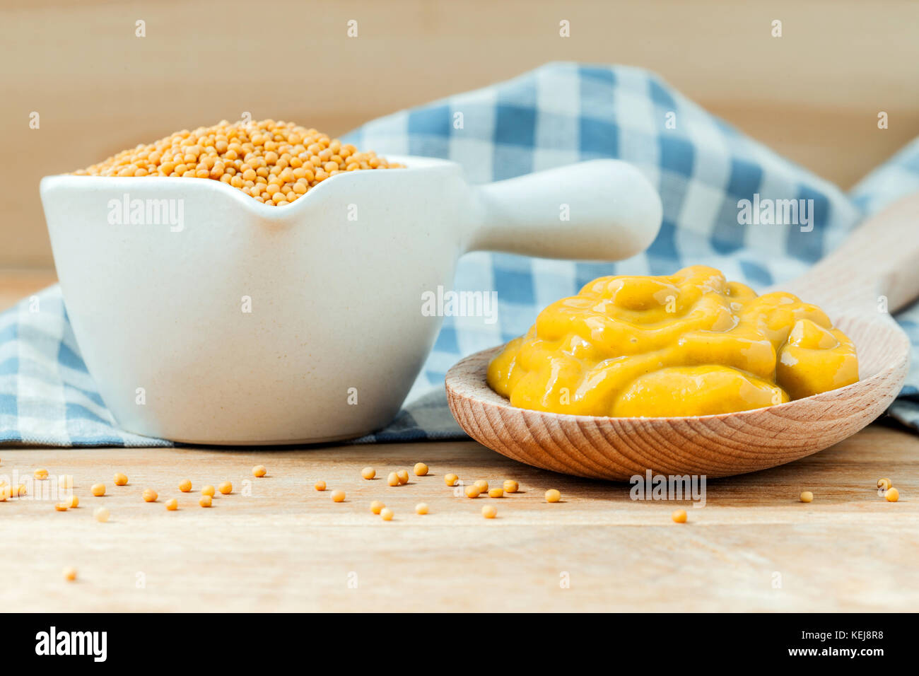 Composition of mustard in wooden spoon and mustard seeds in ceramic ...