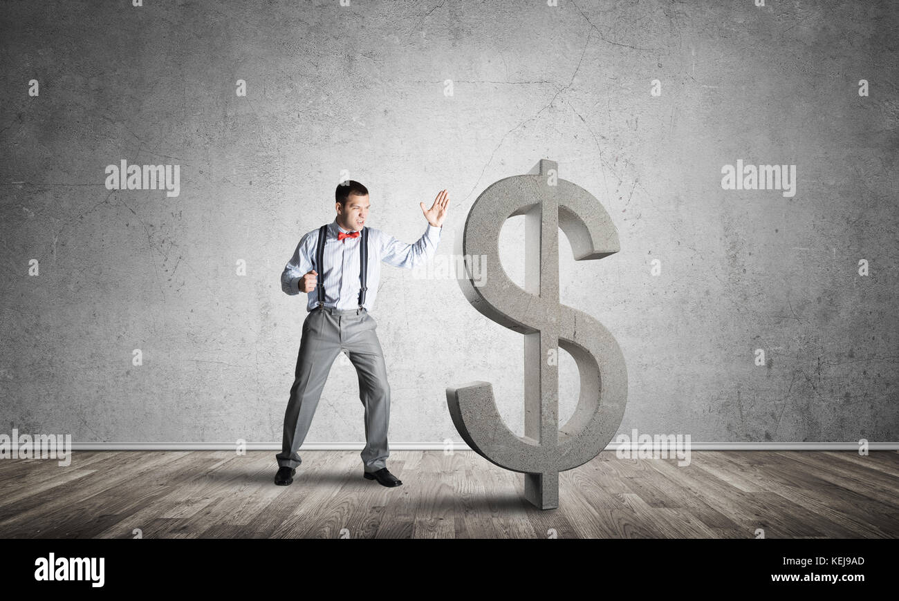 Determined banker man in empty concrete room breaking dollar figure ...