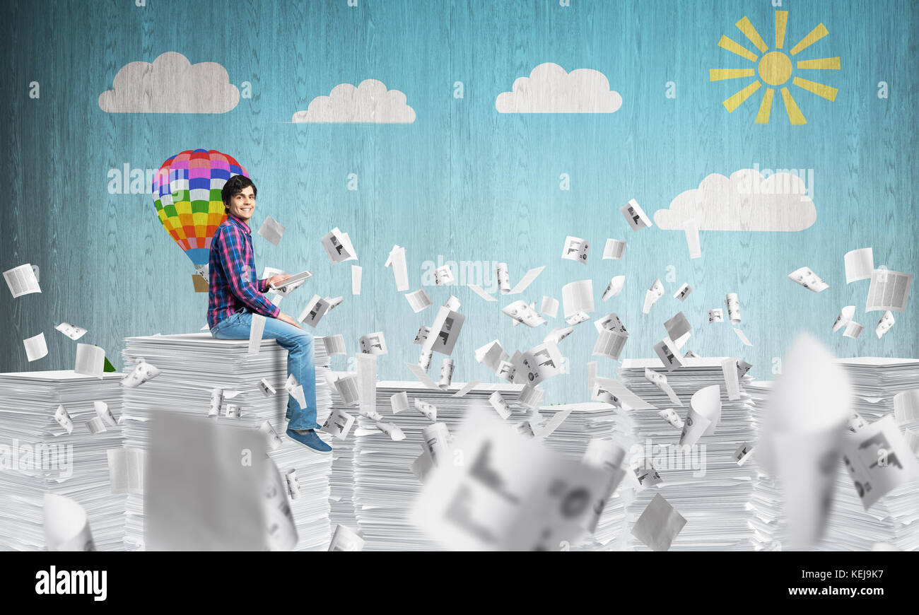 Young man sitting on pile of paper documents Stock Photo - Alamy