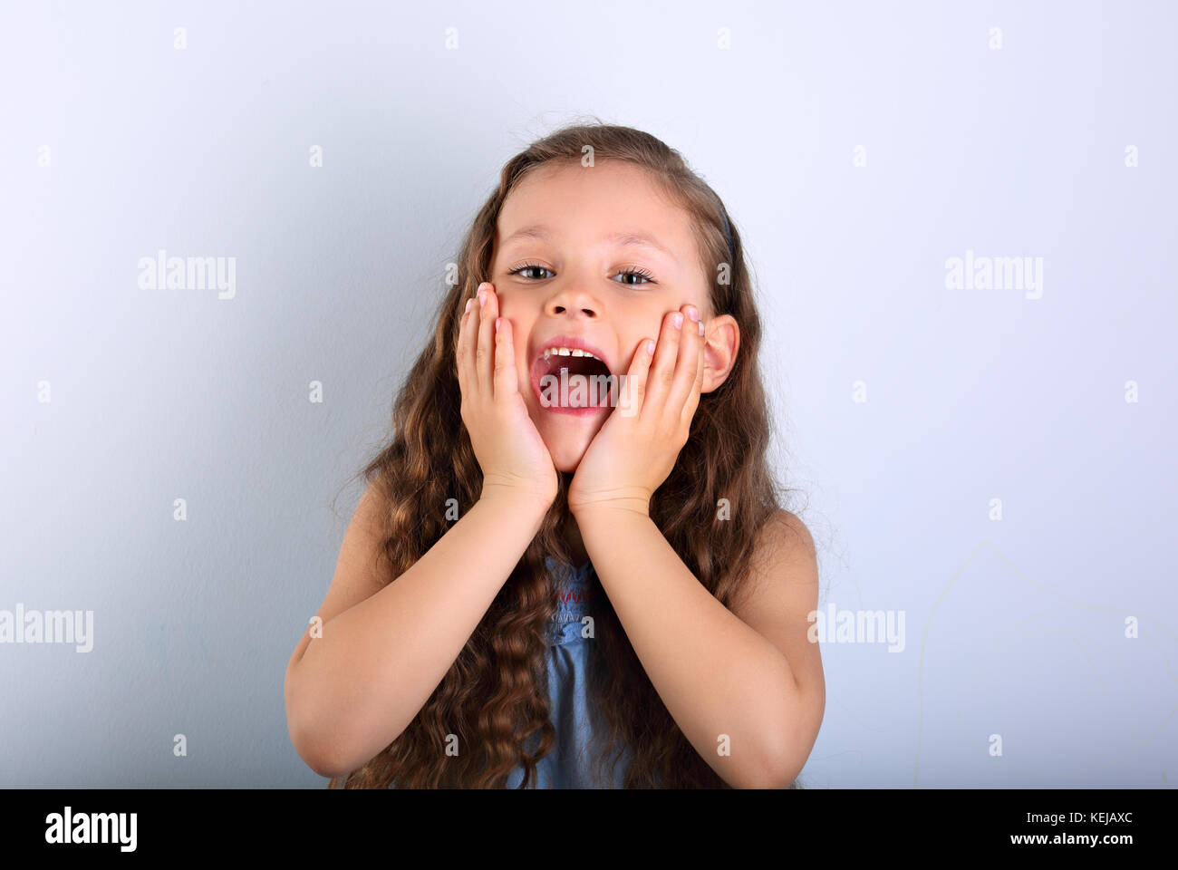 Excited surprising kid girl with wide open mouth and big eyes looking ...