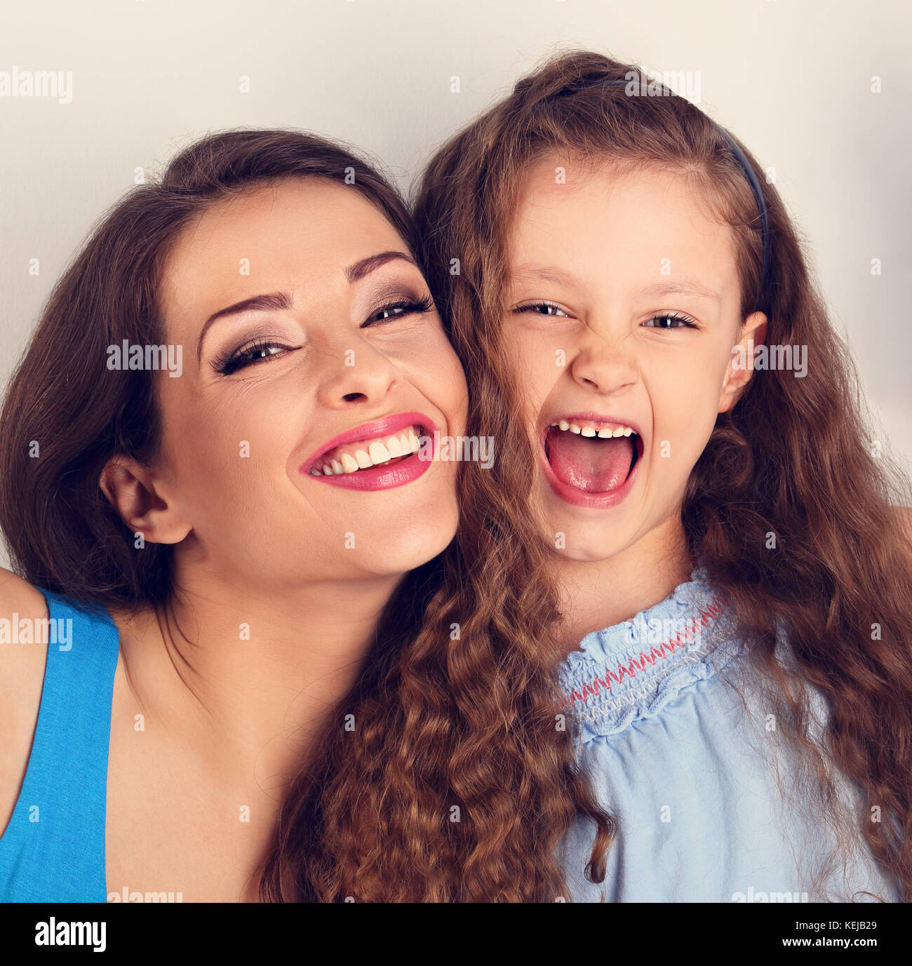 Beautiful happy laughing mother and cute long curly style joying ...