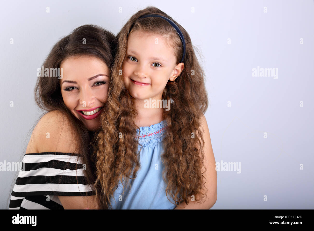 Beautiful happy laughing mother and cute long curly style daughter ...