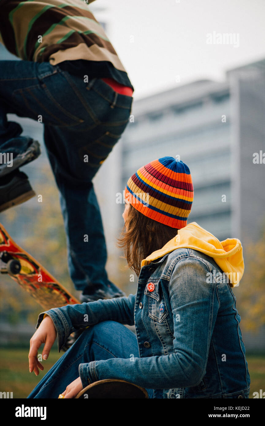 Young girl watching his boyfriend making acrobats with his skateboard ...
