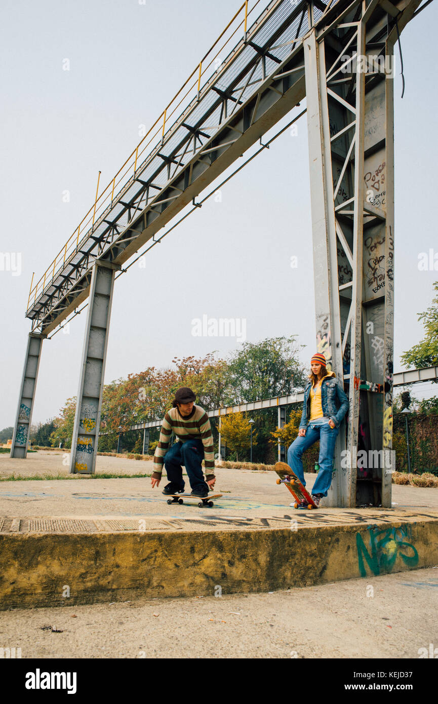 Young girl watching his boyfriend making acrobats with his skateboard ...