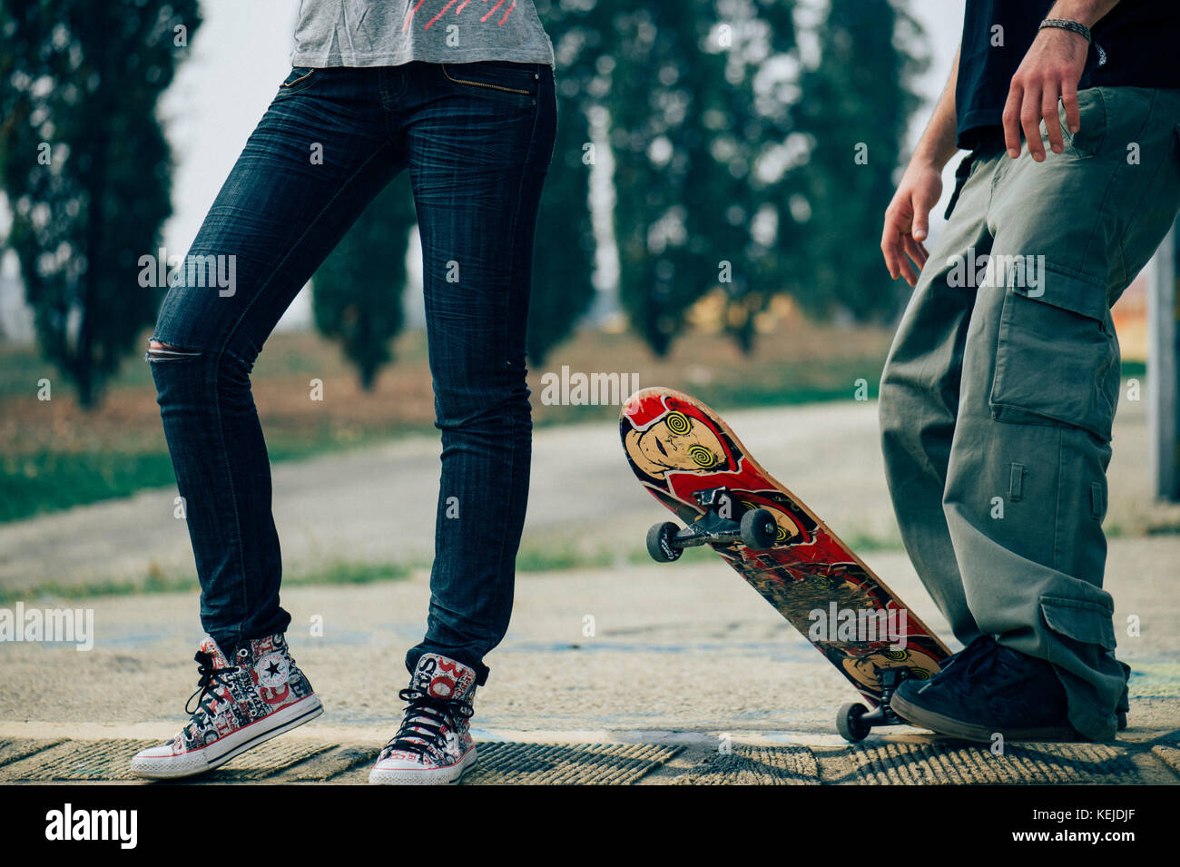 Young girl watching his boyfriend making acrobats with his skateboard ...