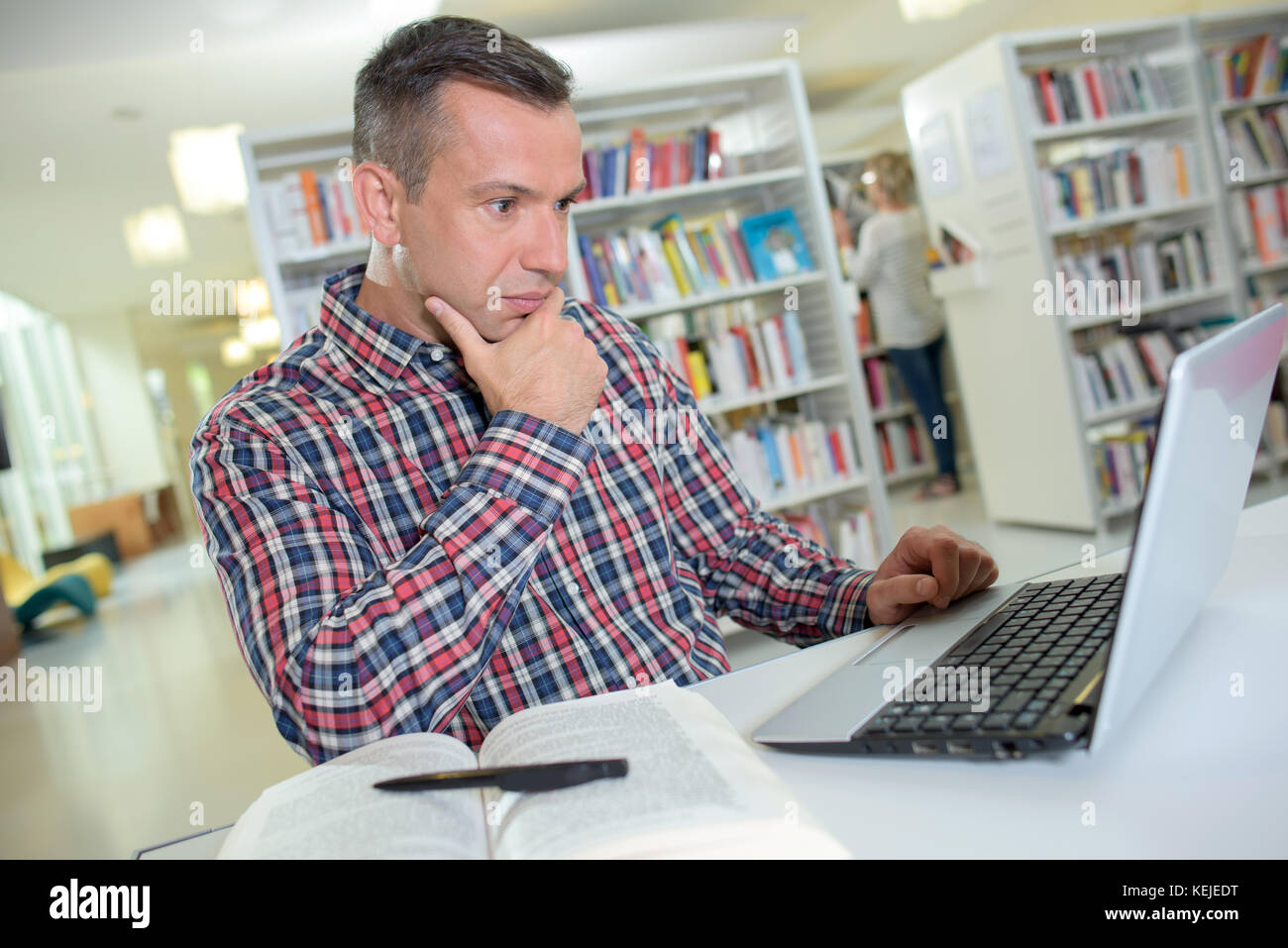 Man in library concentrating using laptop Stock Photo - Alamy