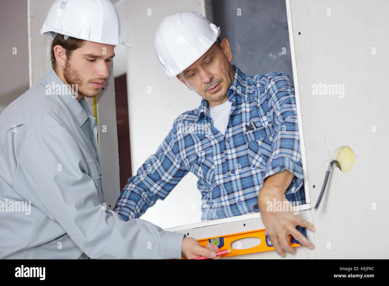 builder and architect inspecting even level of wall Stock Photo - Alamy