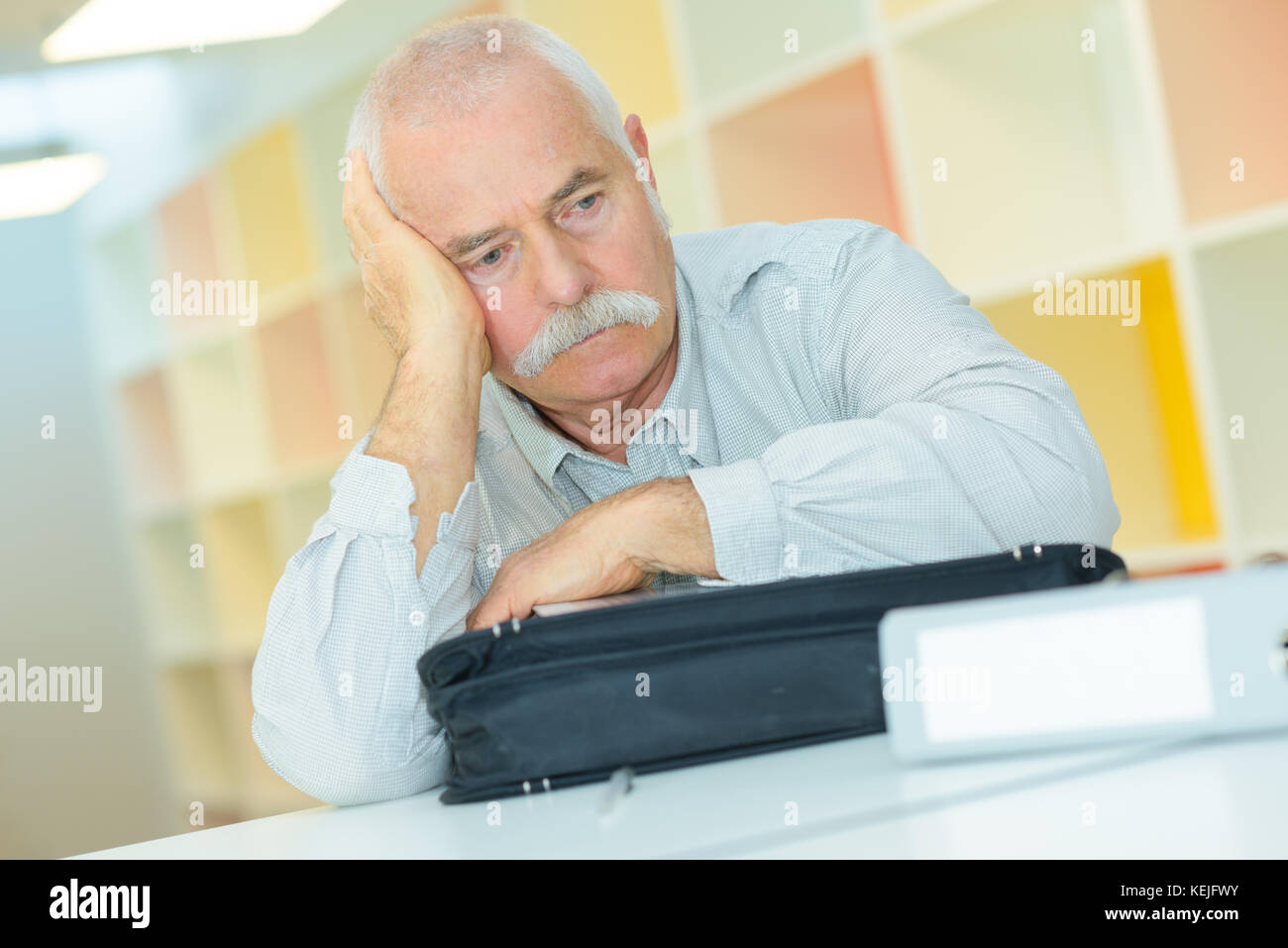 sad senior man sitting at table at the office Stock Photo - Alamy