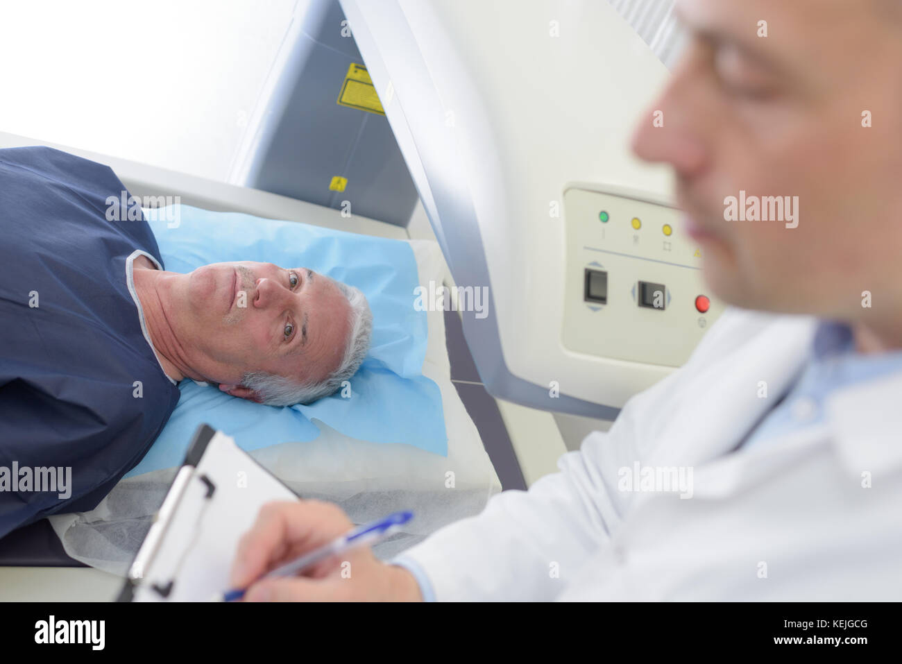 Doctor making notes while patient is under scanning machine Stock Photo ...
