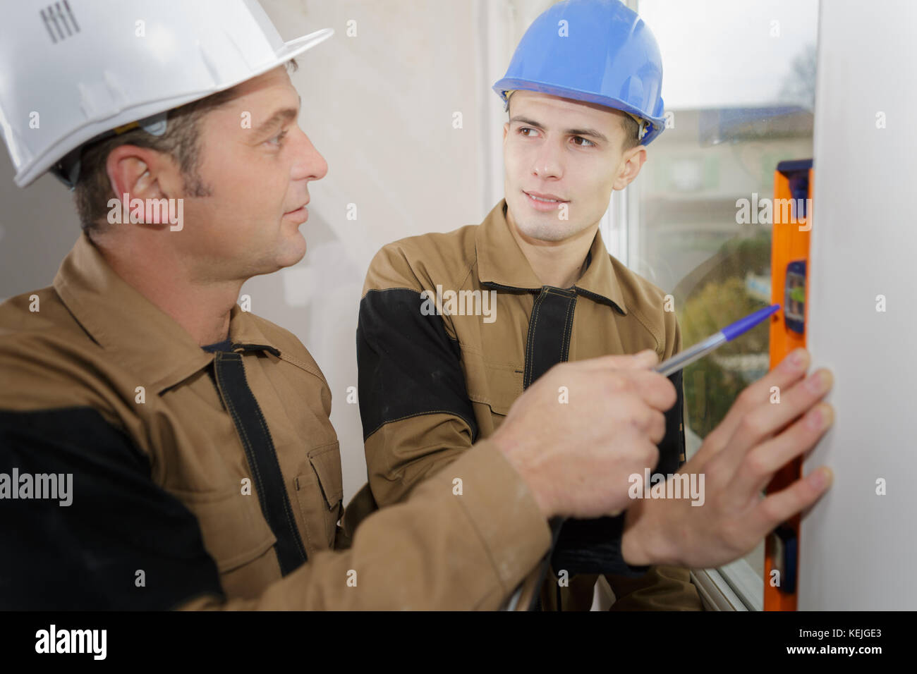 builder with spirit level talking to colleague Stock Photo - Alamy