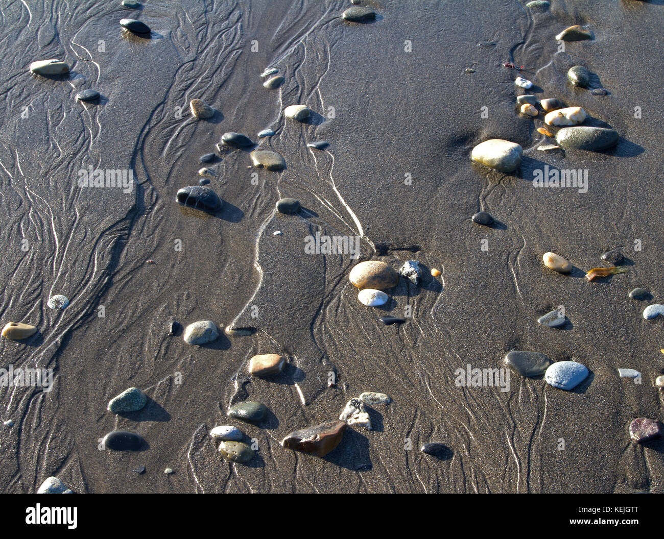 Pebbles and water patterns on beach Stock Photo - Alamy