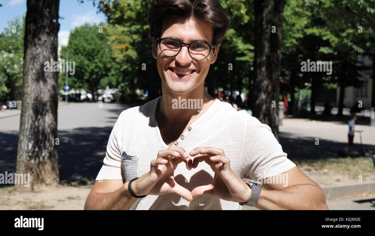 Handsome young man making heart sign with his hands and fingers ...