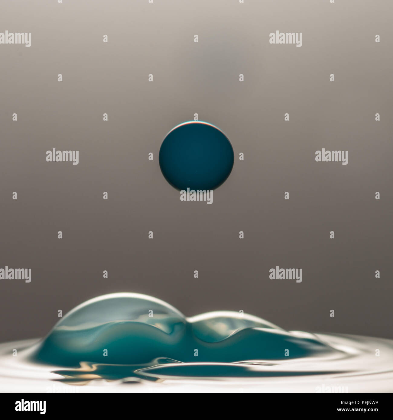 A coloured droplet of milk falls towards a full glass of milk Stock ...