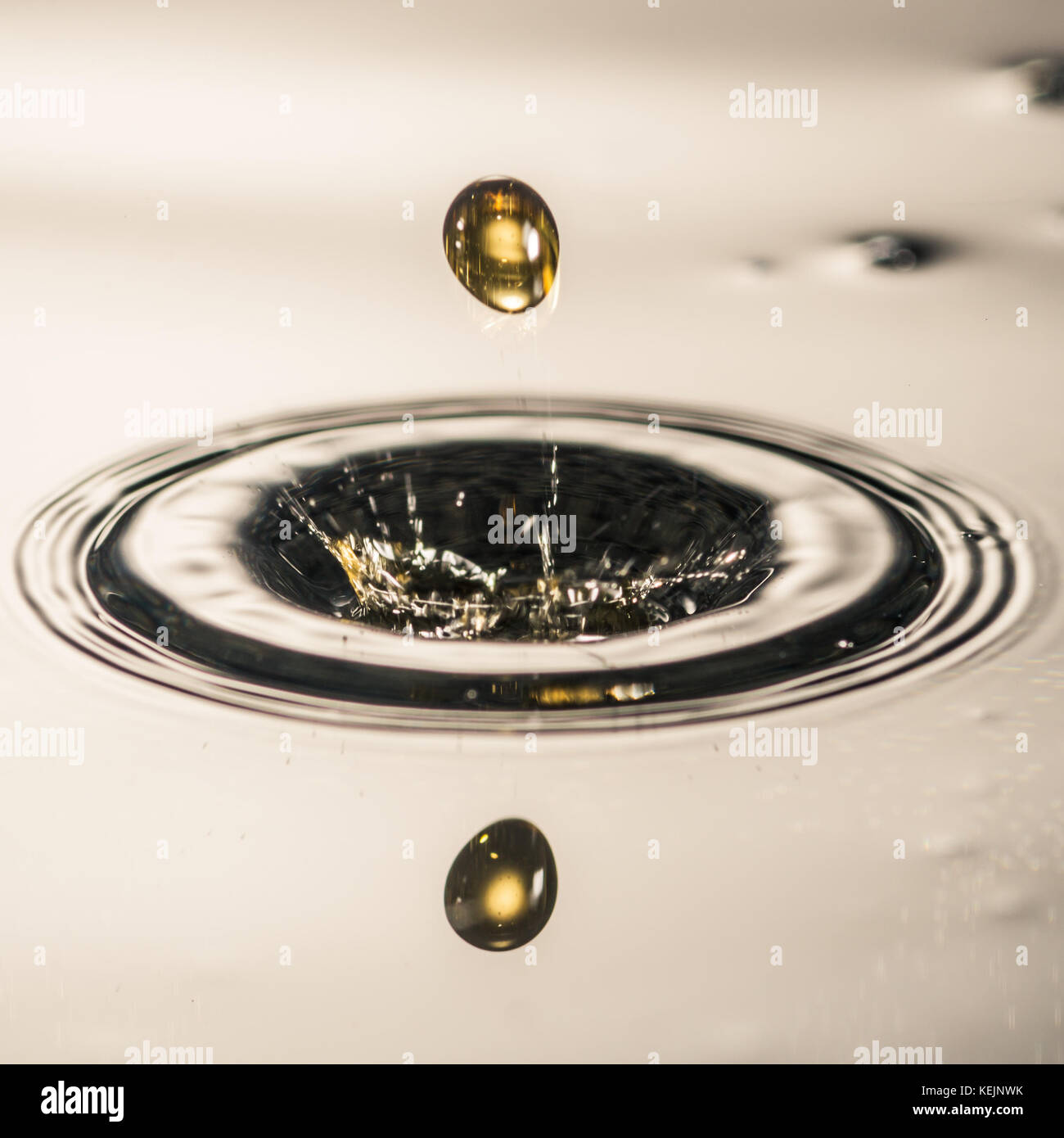 A colourful water drop falls into the surface of a pool of water Stock ...