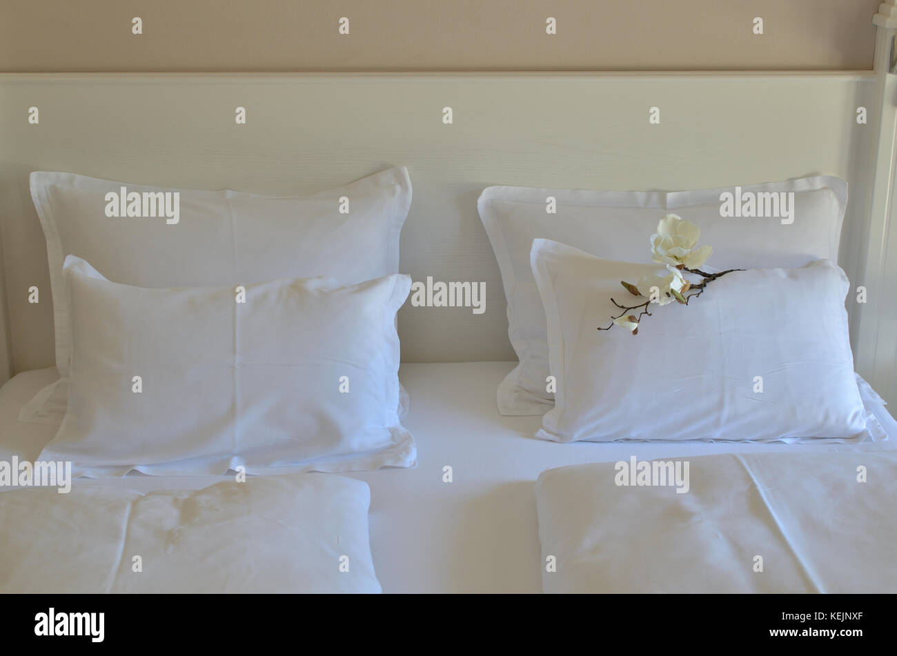 Matrimonial bed with snow white sheets with an artificial orchidea on a ...