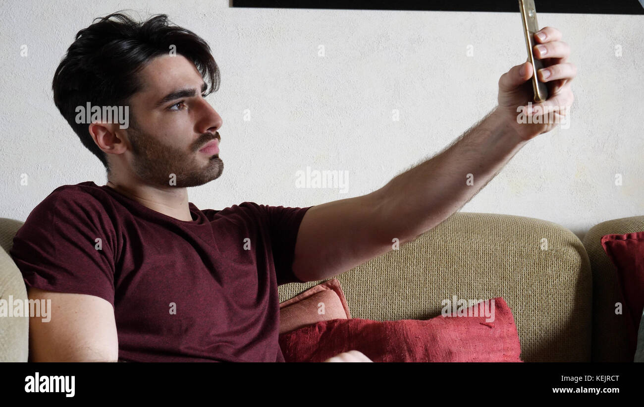 Attractive young man using cell phone to take selfie photo and send it ...