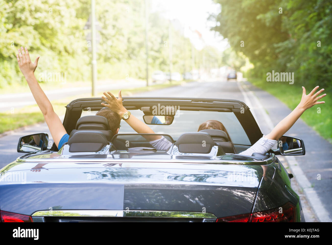 Rear View Of A Couple Sitting In A Car Raising Their Car Stock Photo ...