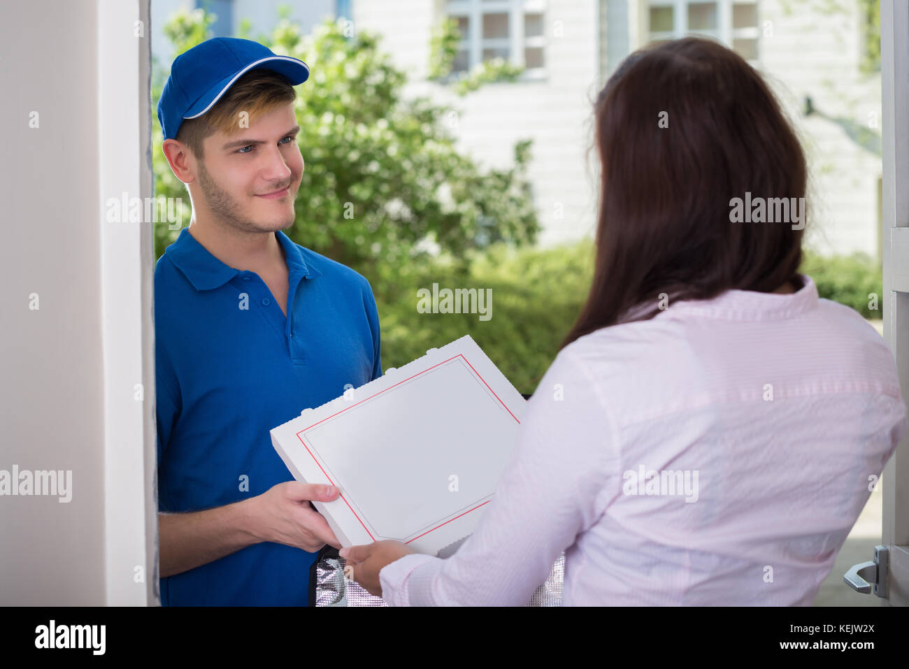 Friendly Delivery Man Handing Pizza To A Customer Stock Photo - Alamy