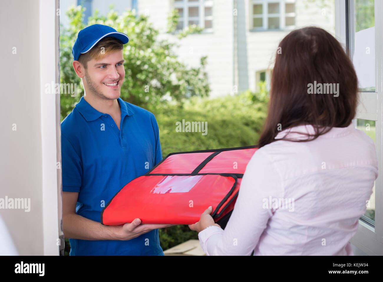 Friendly Delivery Man Handing Pizza To A Customer Stock Photo - Alamy