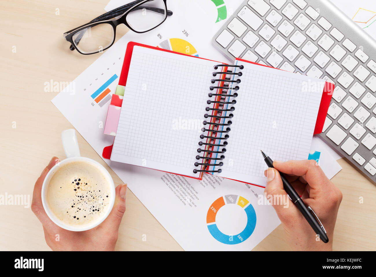 Woman working with reports and charts over wooden office desk. Top view ...