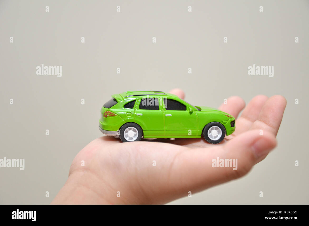 Green toy car on a right hand with white background Stock Photo - Alamy