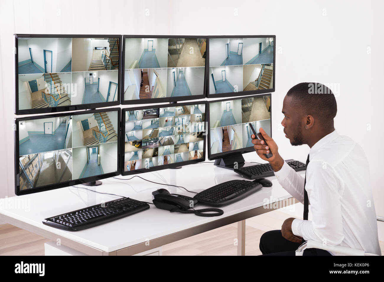 Male Operator Talking On Walkie-Talkie While Looking At CCTV Footage ...