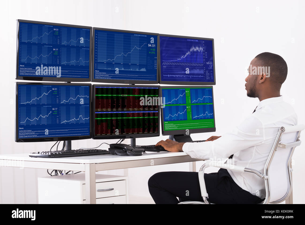 Businessman Analyzing Data Displayed On Multiple Computer Screens In Office Stock Photo - Alamy