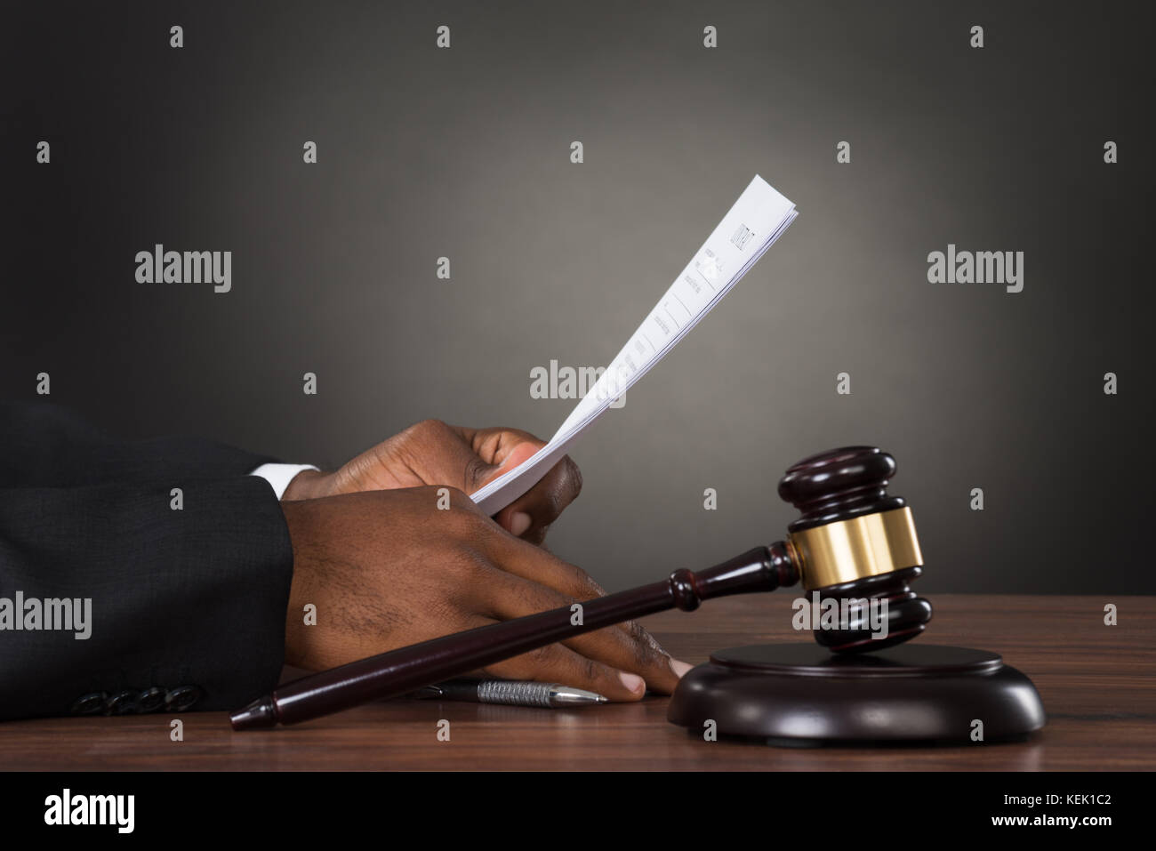 Close-up Of A Judge Holding Paper With Gavel At Wooden Desk Stock Photo ...