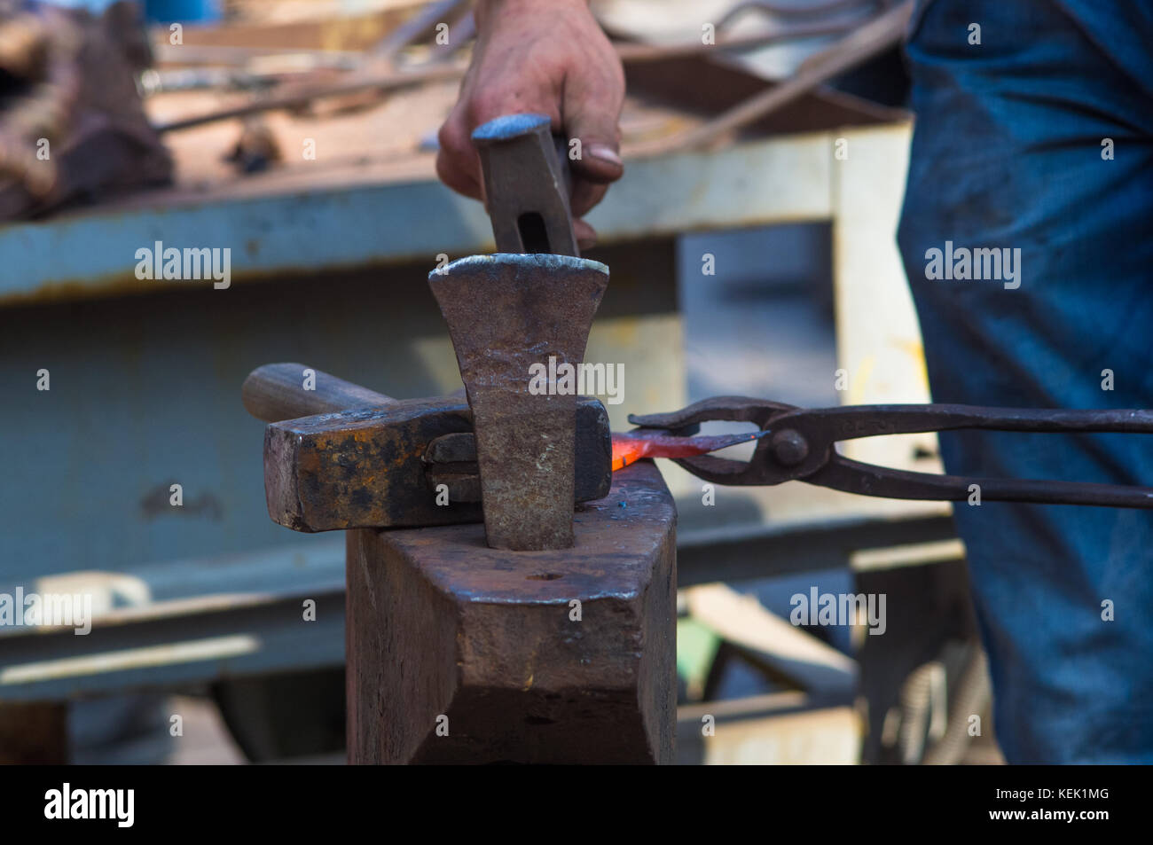blacksmith performs the forging of hot glowing metal on the anvil ...