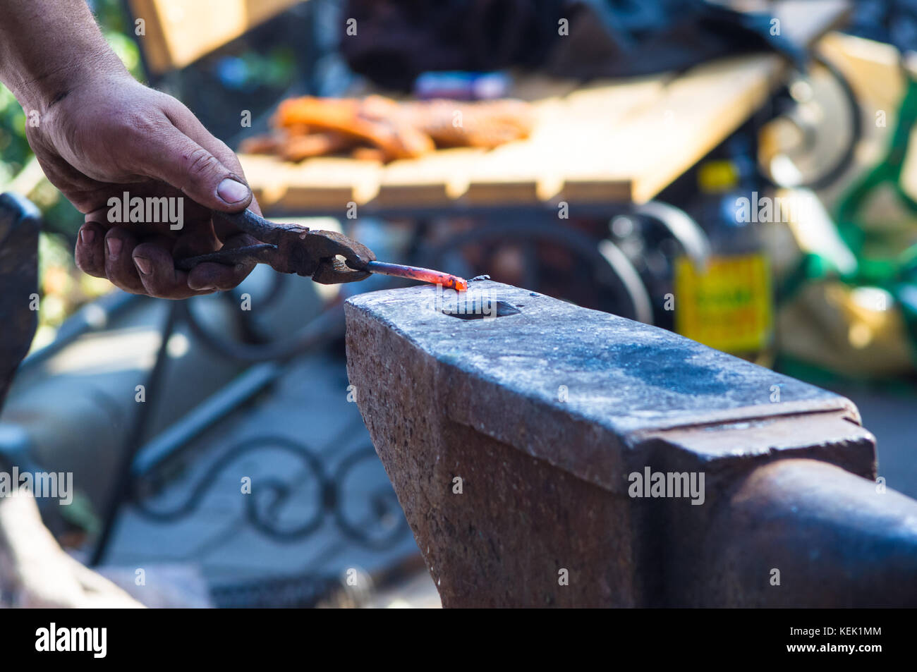 blacksmith performs the forging of hot glowing metal on the anvil ...