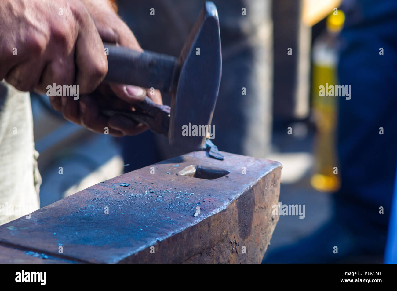 blacksmith performs the forging of hot glowing metal on the anvil ...
