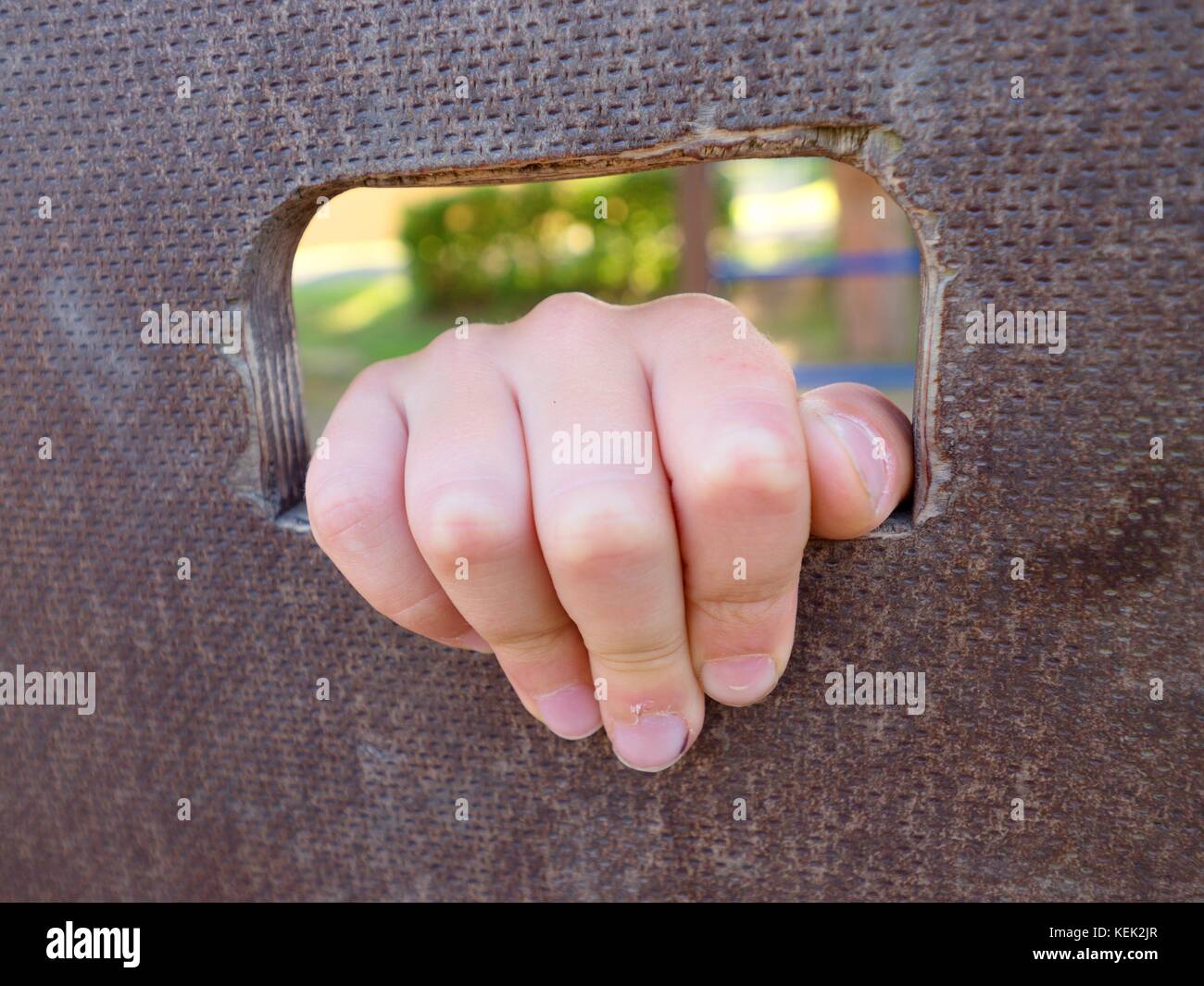 Children hand holds a hole on the wooden climbing wall. Short fingers ...