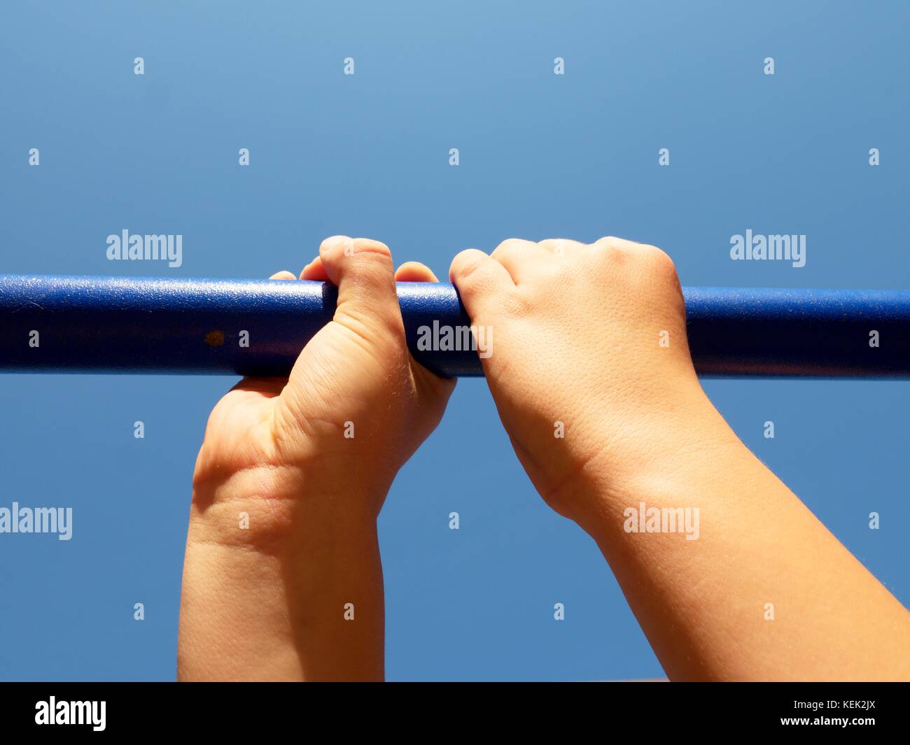 Hold on to monkey bars at playground. Kid is holding blue steel bar ...