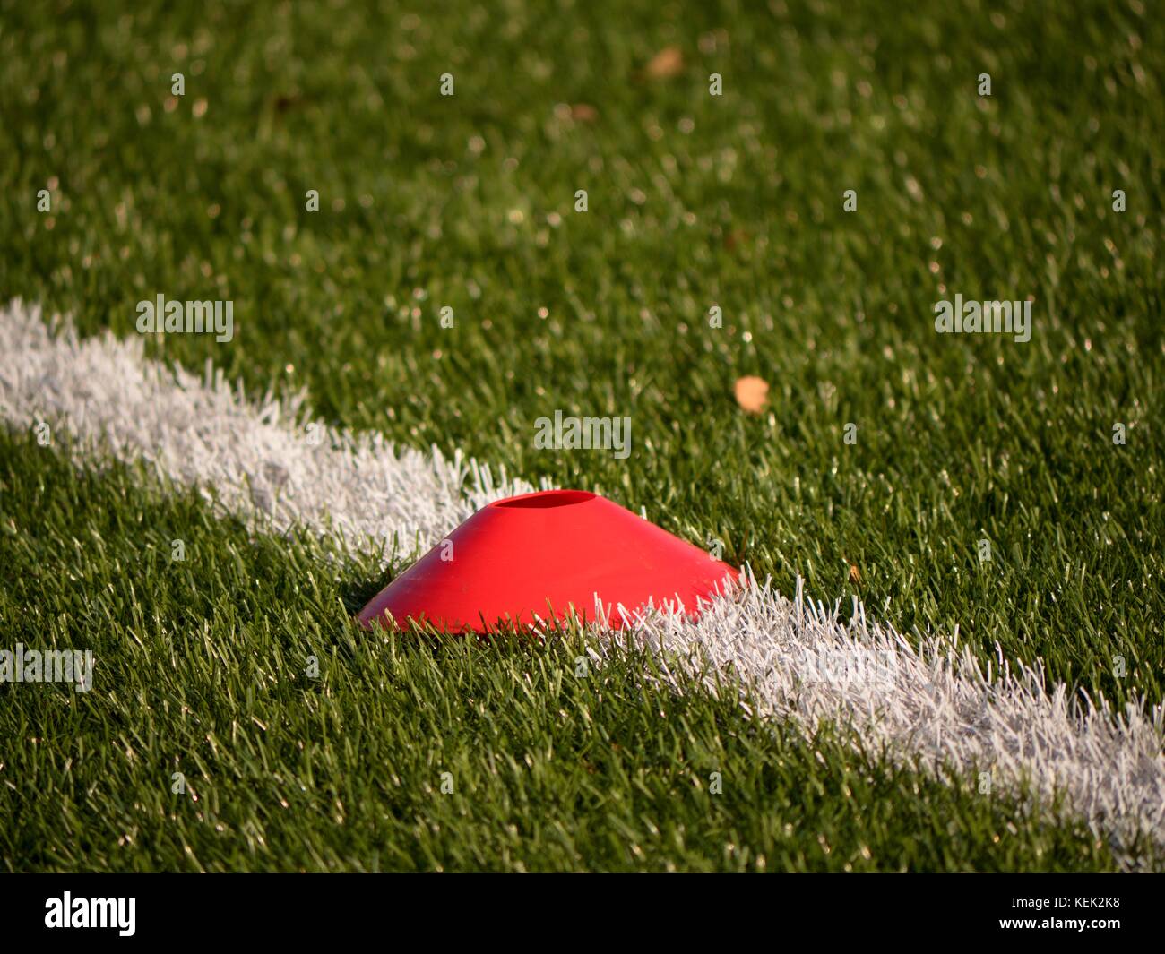 Bright red plastic cone on painted white line of soccer field. Plastic ...