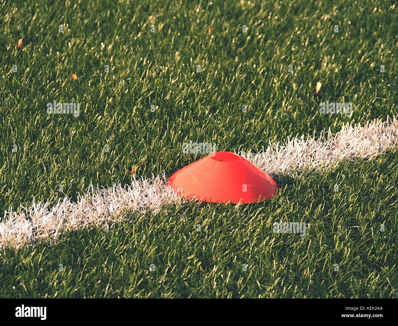 Bright red plastic cone on painted white line of soccer field. Plastic ...