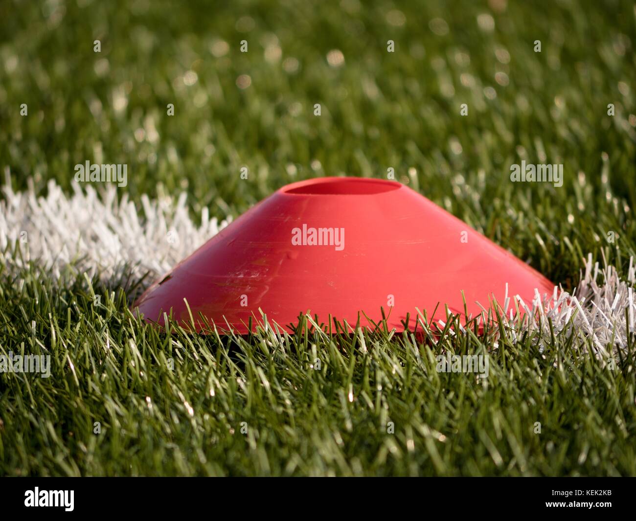 Bright red plastic cone on painted white line of soccer field. Plastic ...