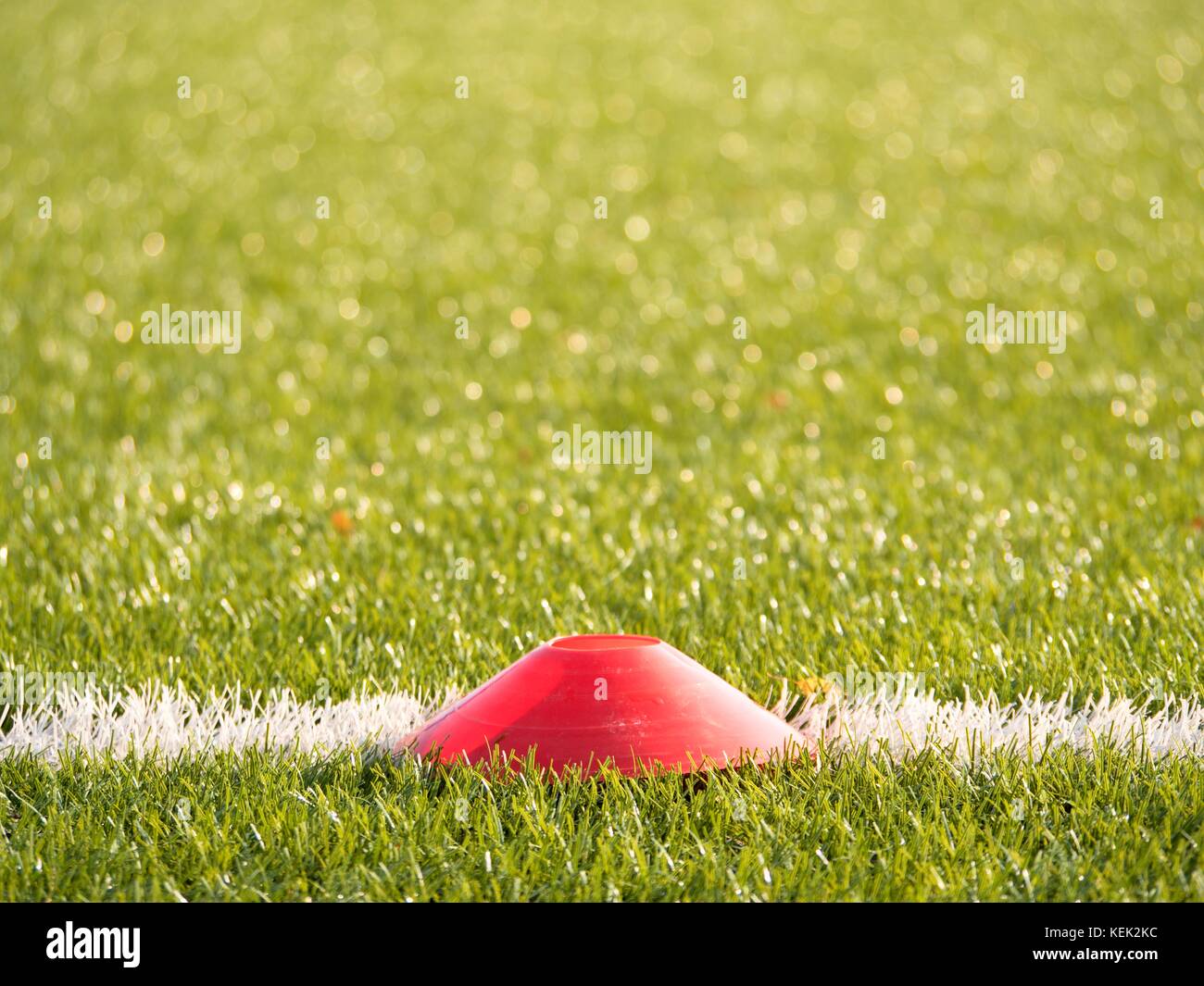 Bright red plastic cone on painted white line of soccer field. Plastic ...