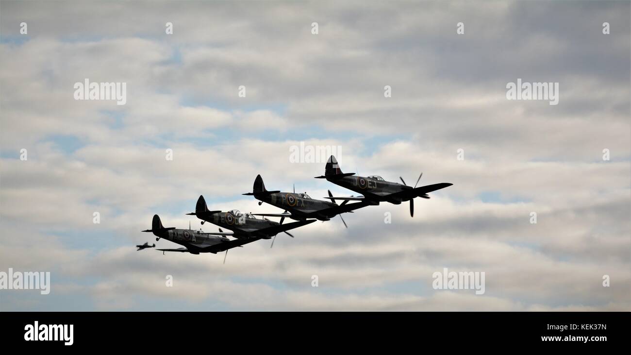 4 Spitfire fighters fly past in the clouds Stock Photo - Alamy